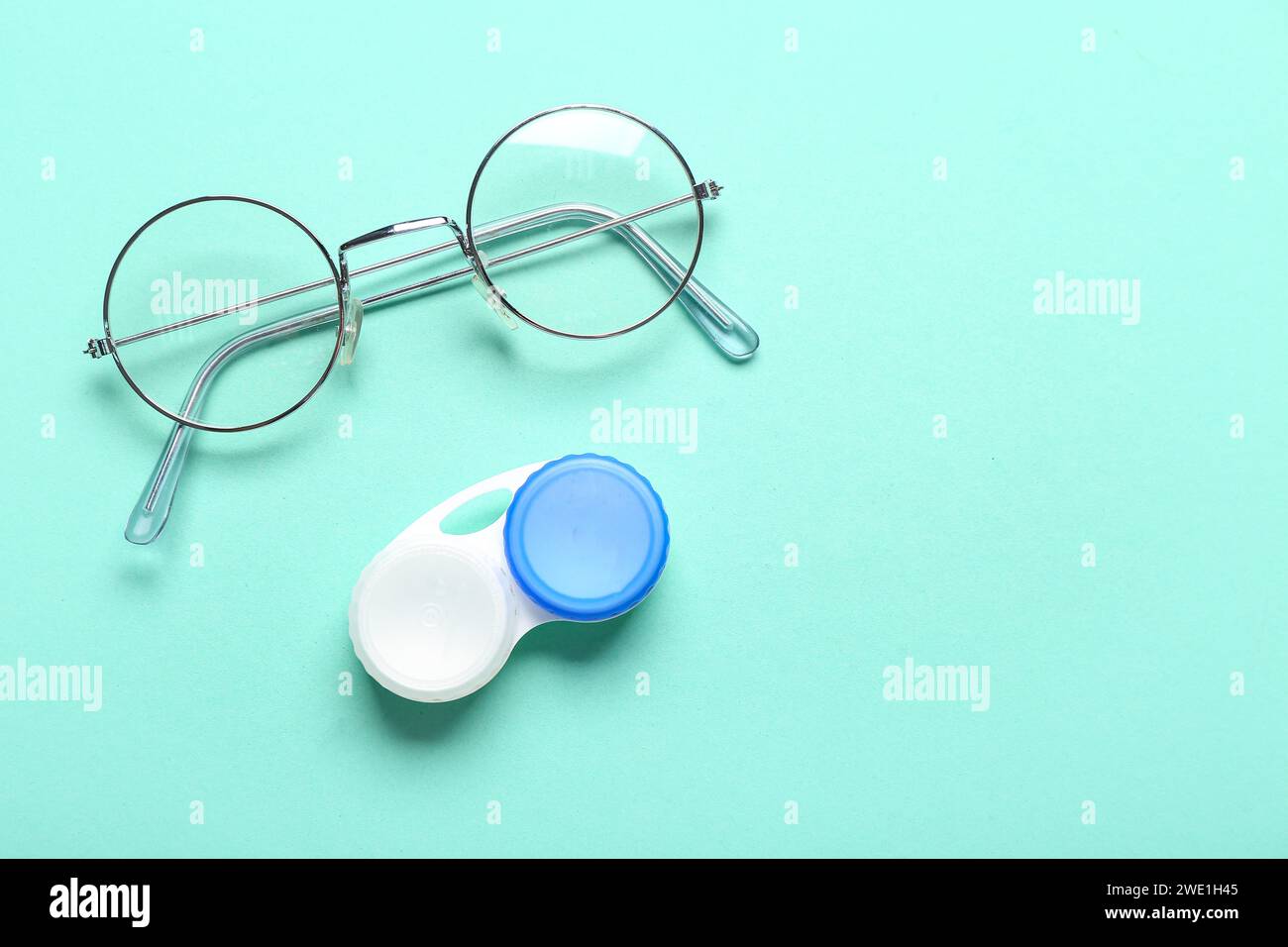 Eyeglasses and container for contact lenses on turquoise background ...