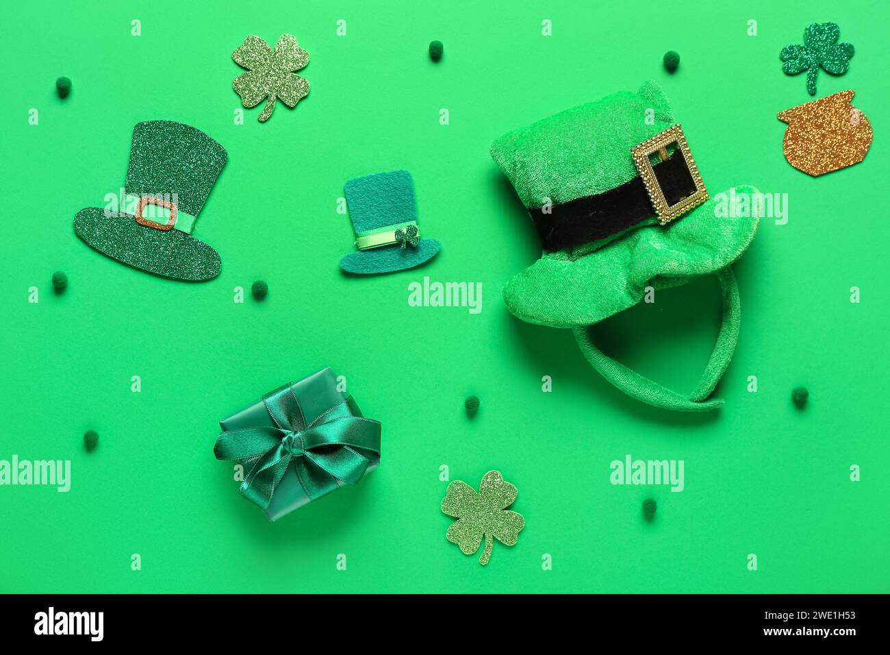 Paper clovers with leprechaun's hats and gift box on green background ...