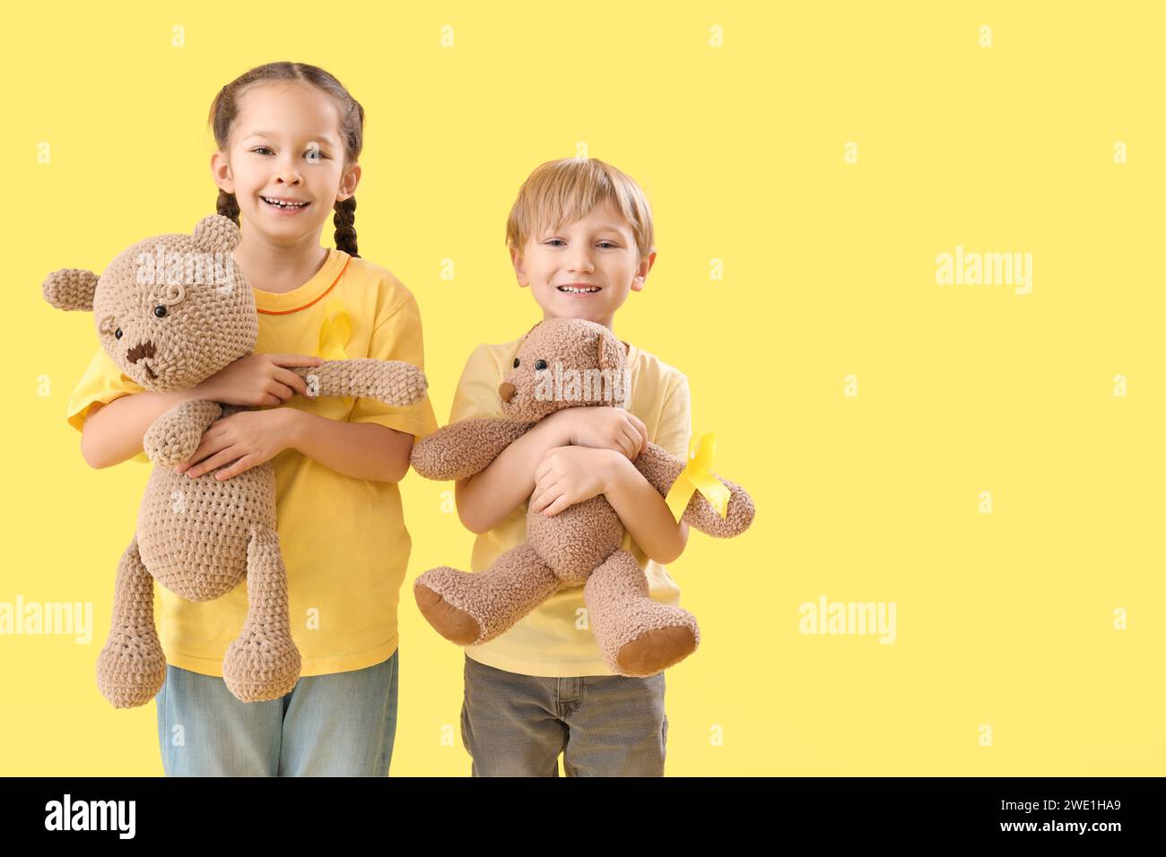 Cute little children with yellow ribbons and teddy bears on color ...