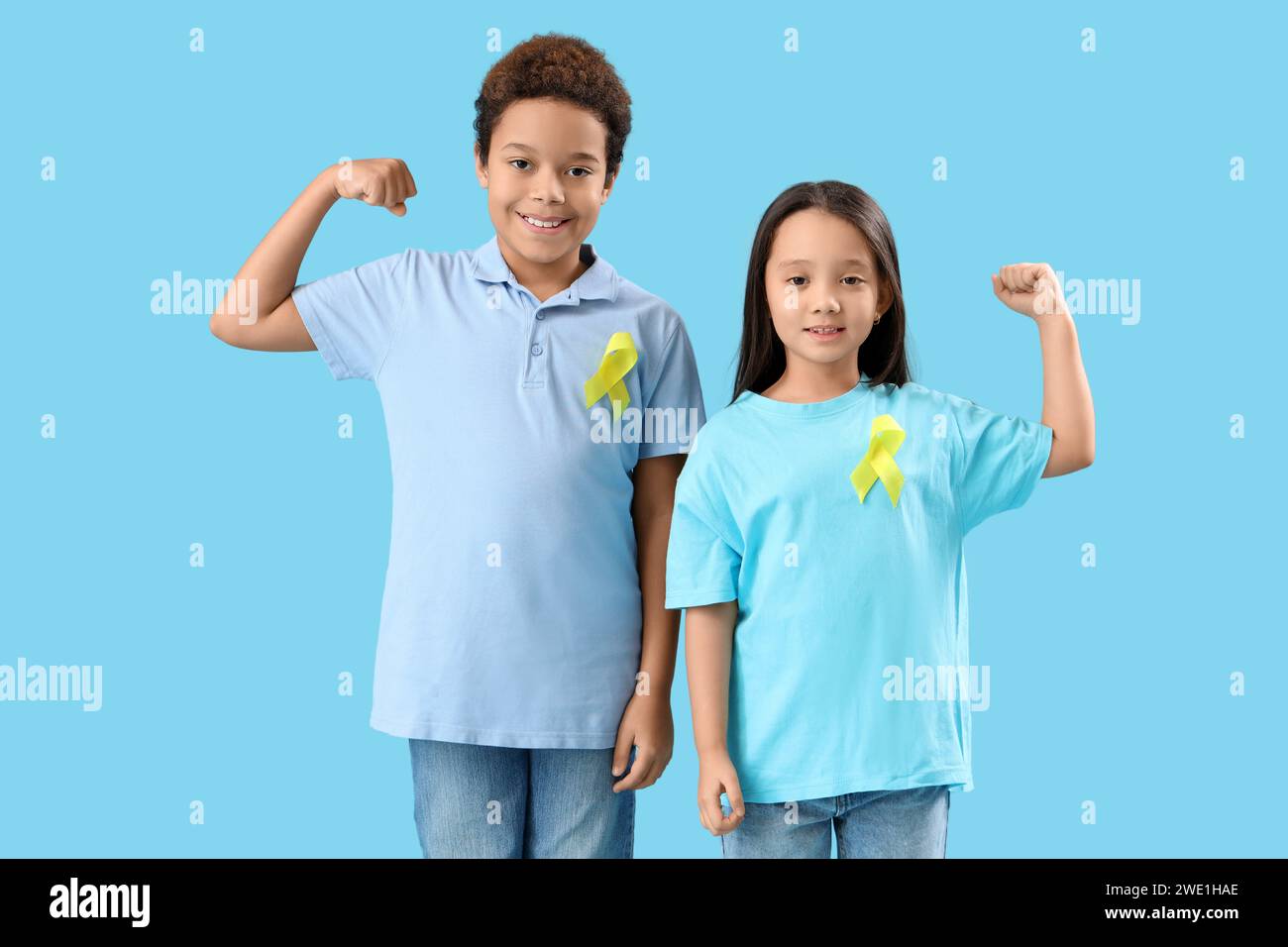Cute little children with yellow ribbons showing muscles on blue ...