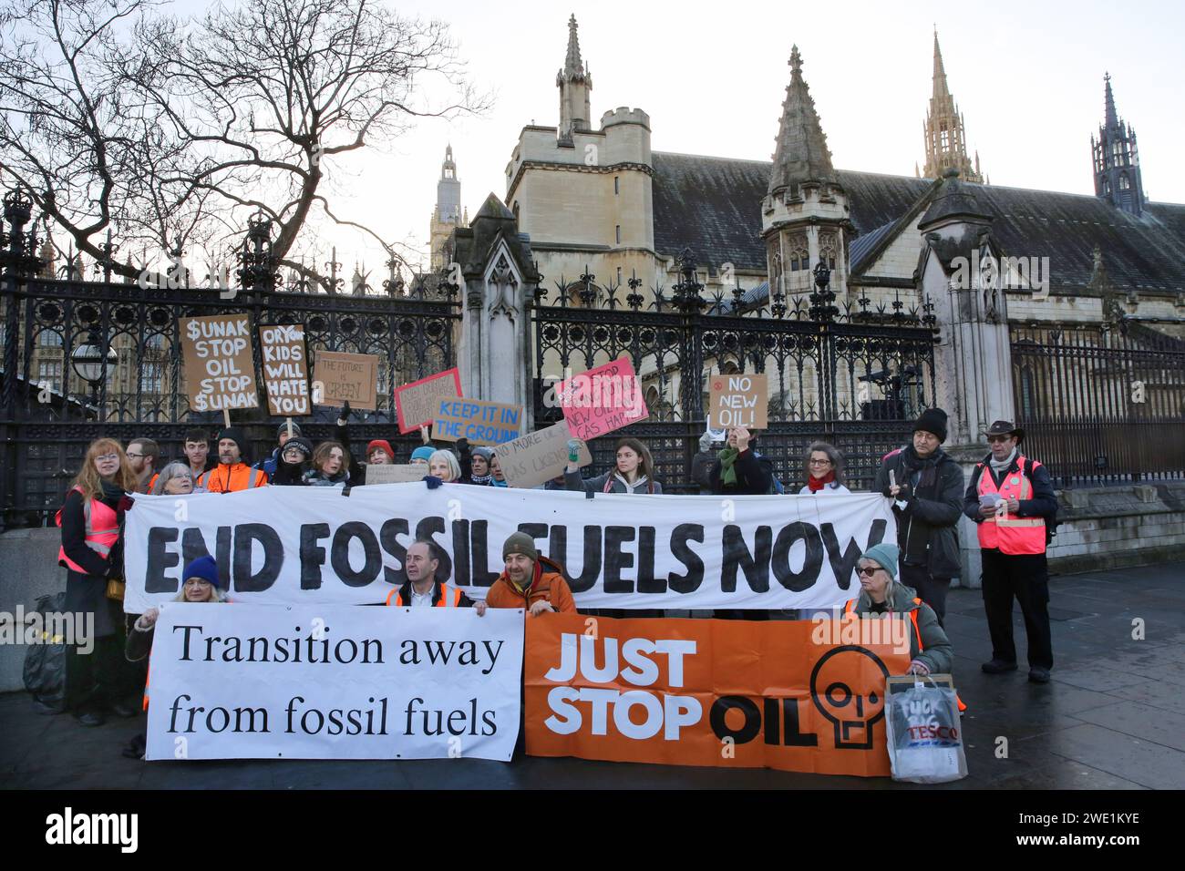 Protesters holds up placards and stand behind anti fossil fuels banners ...