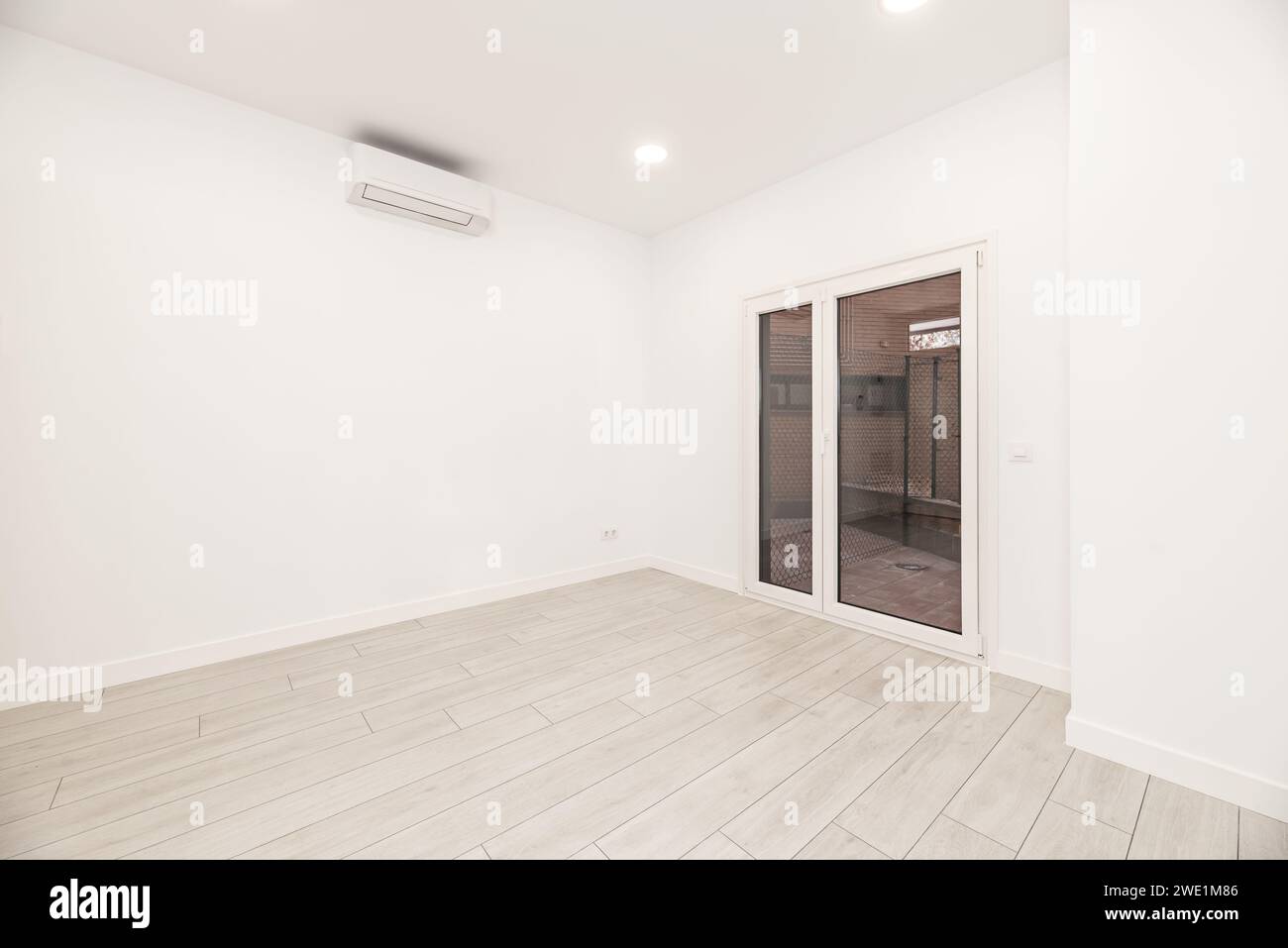 An empty white room in a loft-style home with an aluminum and glass ...