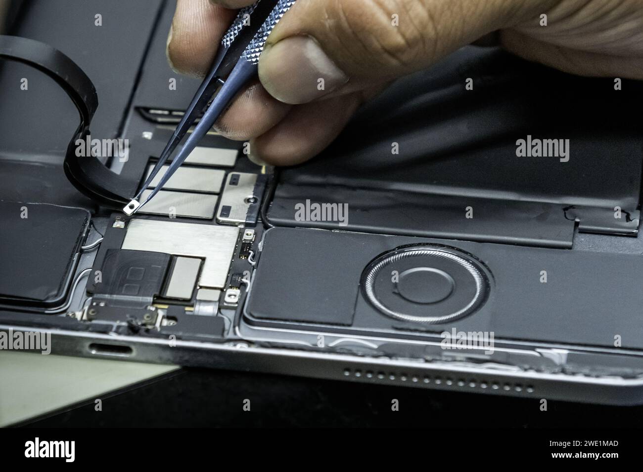 An electronic repair shop technician working with the tiny parts in ...