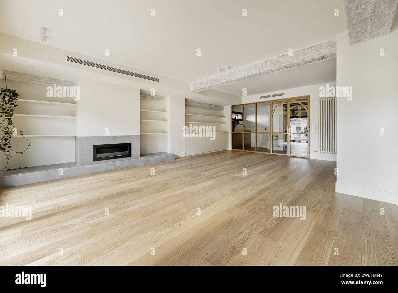 A large empty living room with a wall with a fireplace and plaster ...