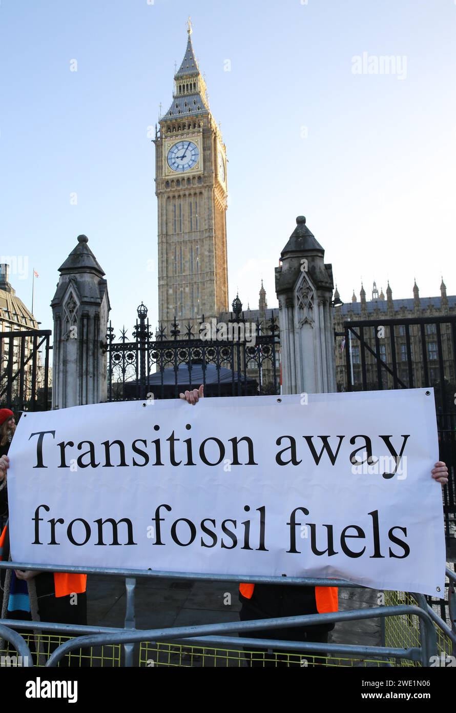 Protesters stand behind a banner reading "Transition Away From Fossil ...