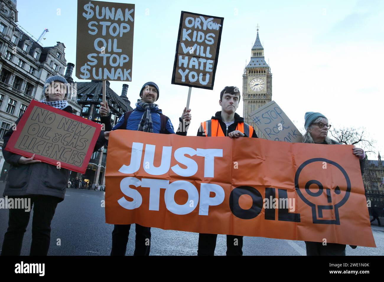 Protesters hold up placards and stand behind a "Just Stop Oil" banner ...
