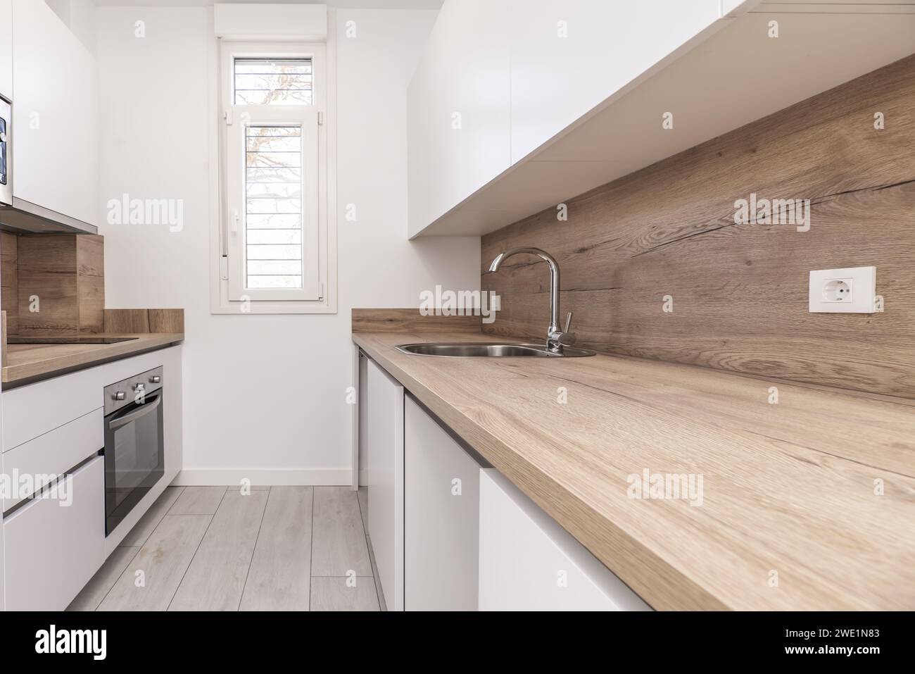 A small kitchen with smooth white furniture without handles and wooden ...