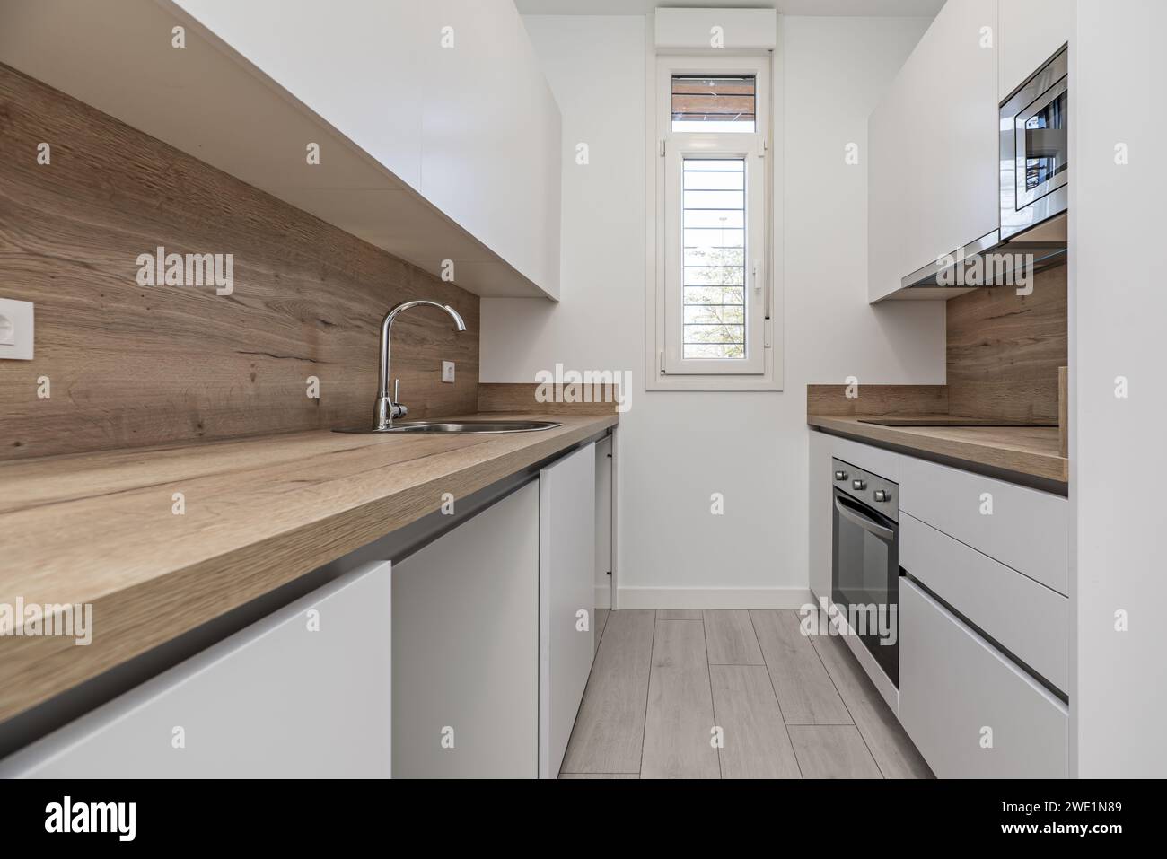 A small kitchen with smooth white furniture, wooden countertops that ...