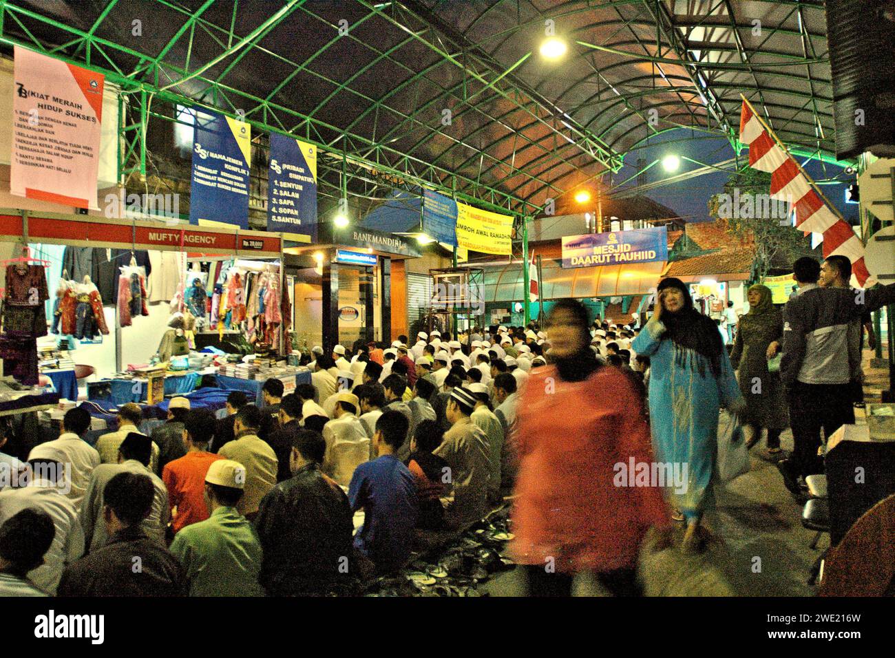 People walk on a space behind congregation during Maghrib prayer at a ...