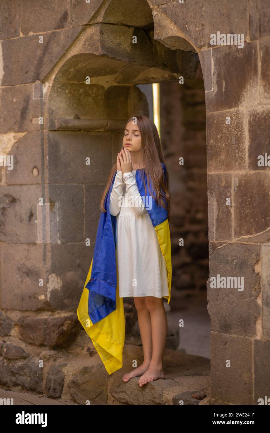 Girl praying wrapped in Ukrainian flag Stock Photo - Alamy