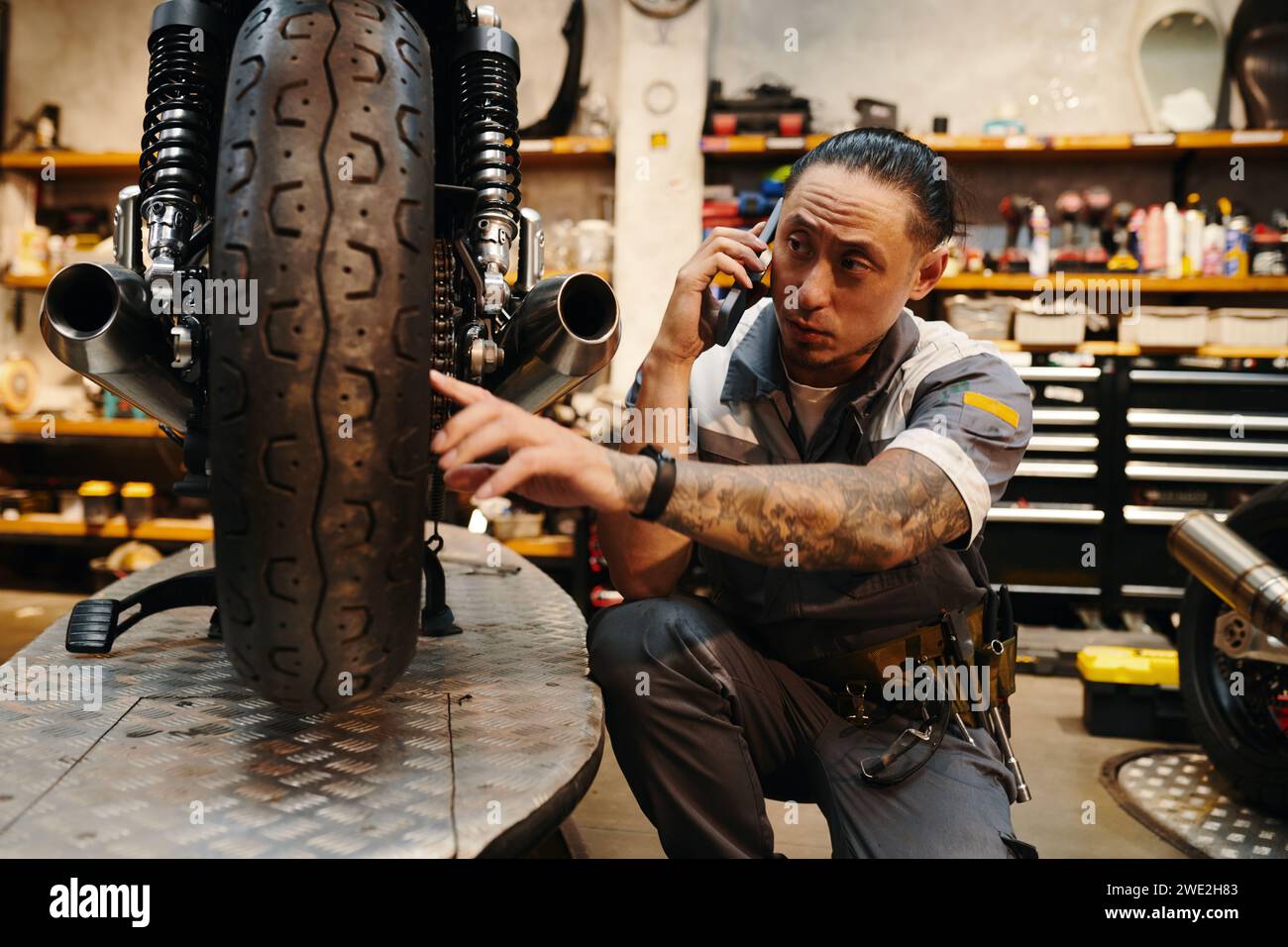 Mechanic calling coworker to discuss better way to fix motorcycle ...