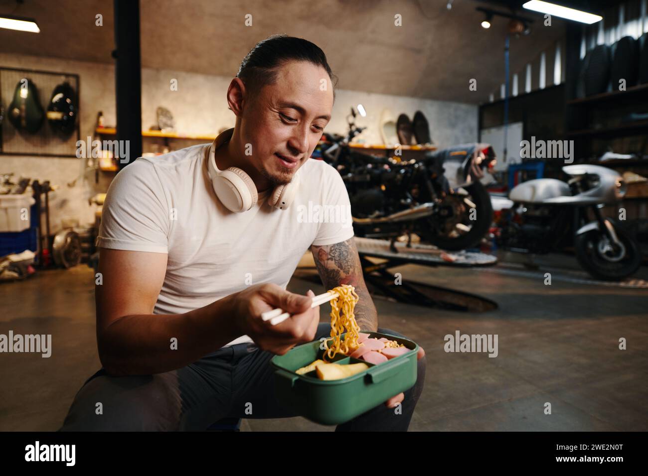 Cheerful repair shop owner eating lunch from container Stock Photo - Alamy