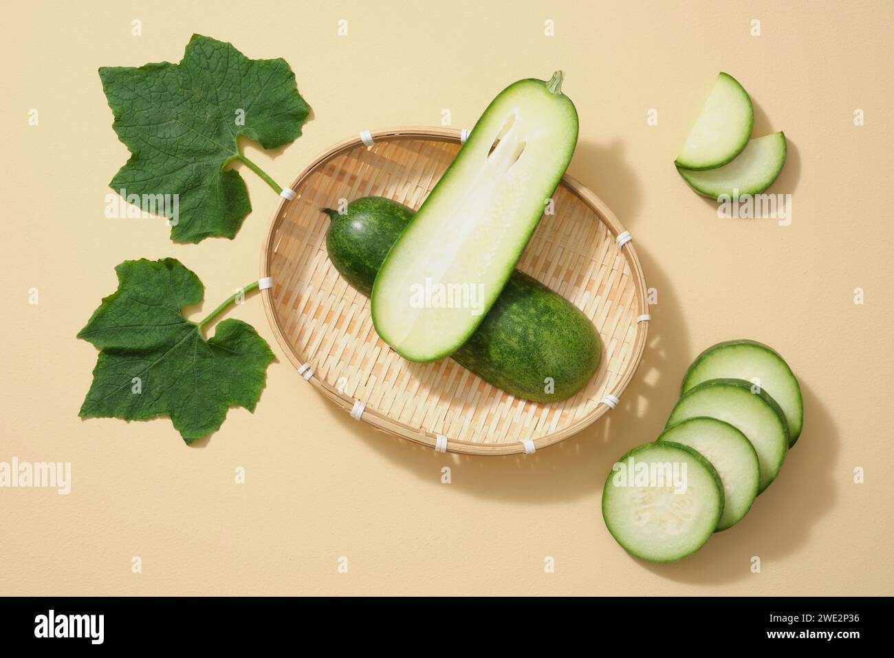 Against a bamboo basket, fresh winter melon cut in half, some slices ...