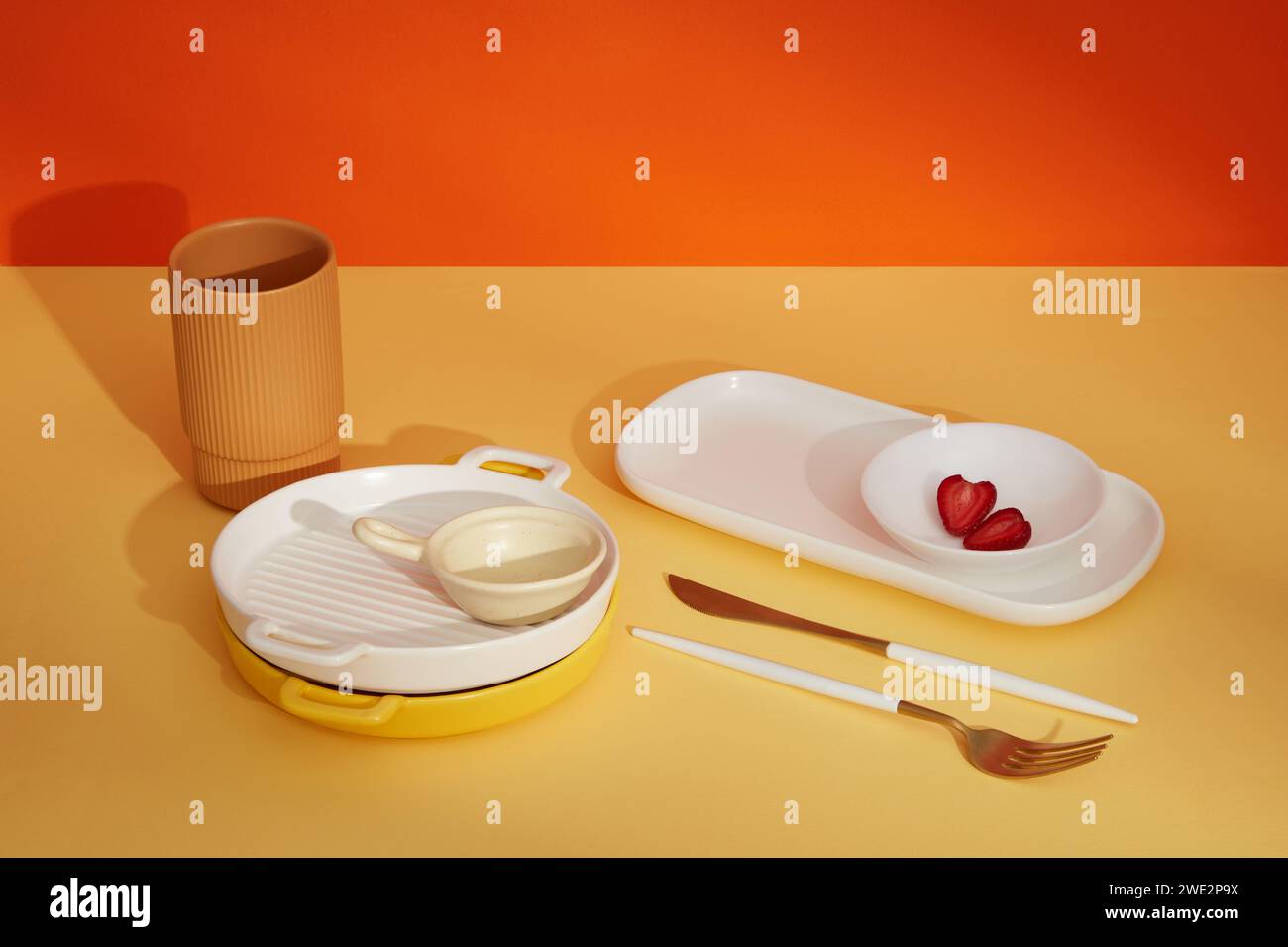 Stacked of pan, white plates, cutlery and strawberry slices decorate on ...