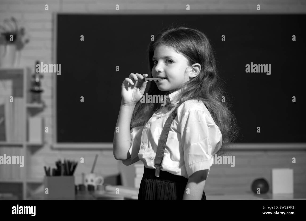 Portrait of cute, lovely, girl in school uniform eating chocolate in ...