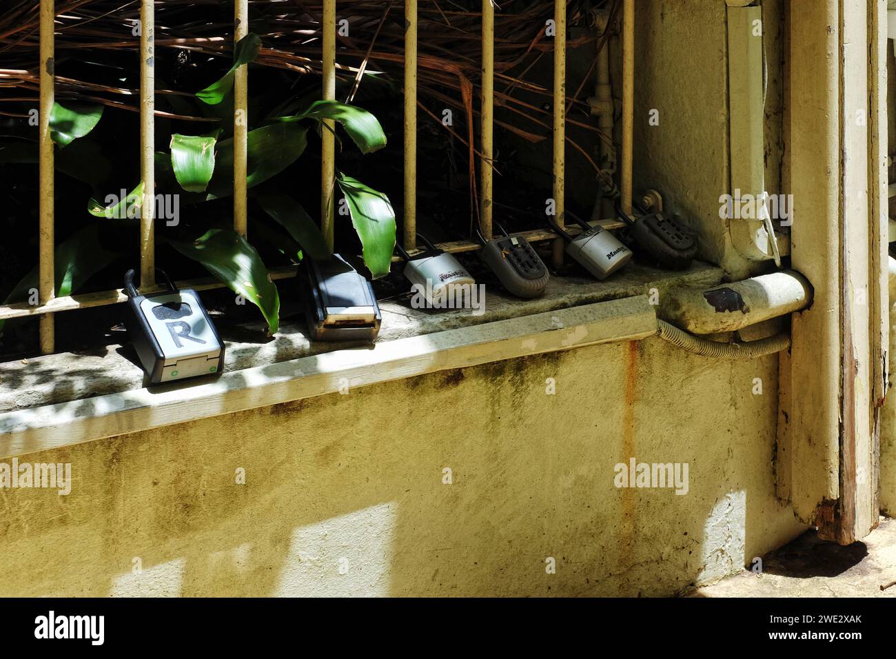 A row of combination lock key safe boxes attached to a metal fence ...