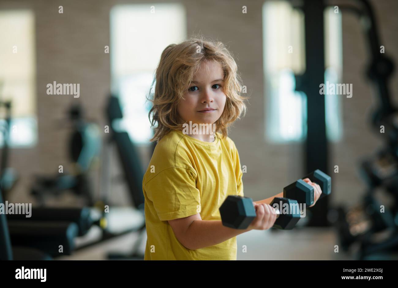 Kid workout kid in gym. Sport activities at leisure with children. Blonde boy holding dumbbells ...