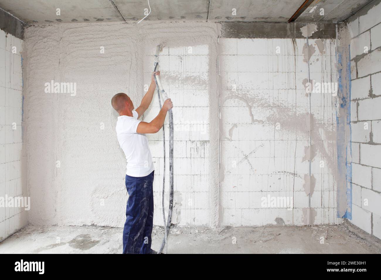 Worker plasterer plastering house walls, finishing walls with spray ...
