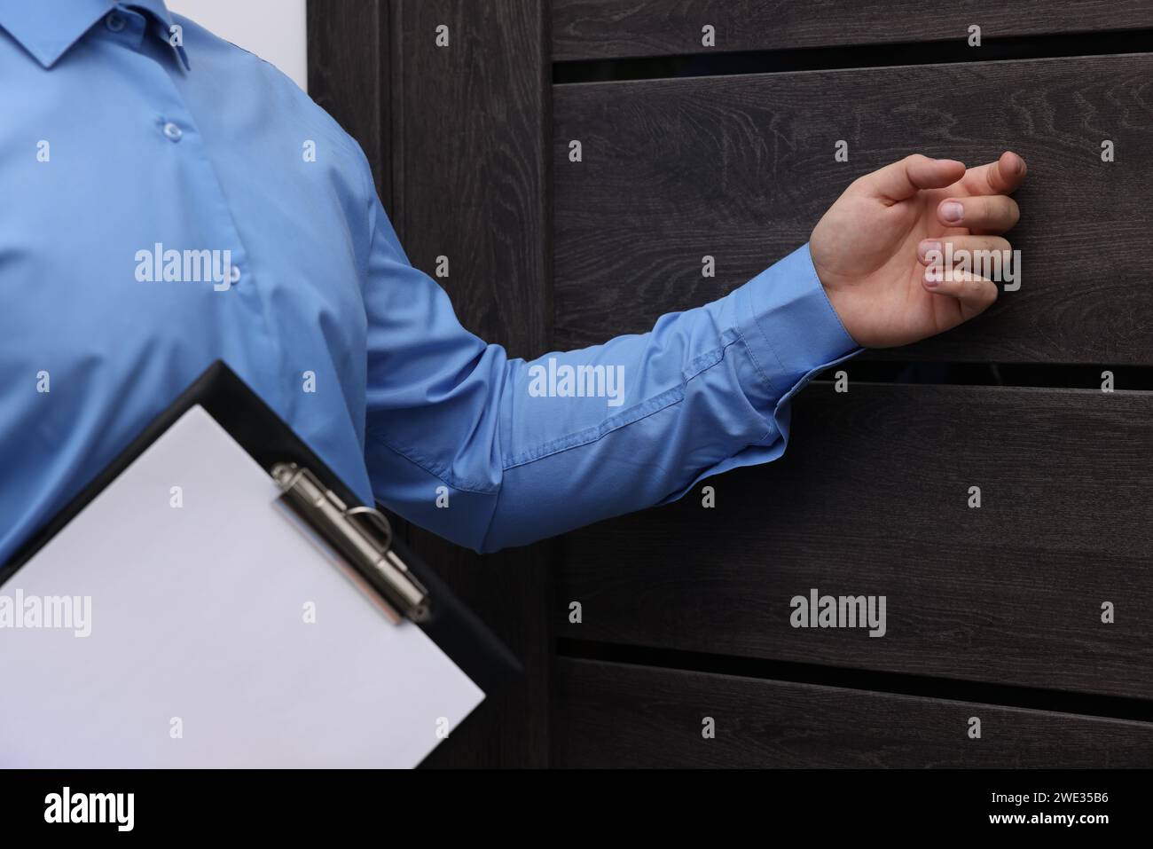 Collection agent with clipboard knocking on wooden door, closeup Stock ...