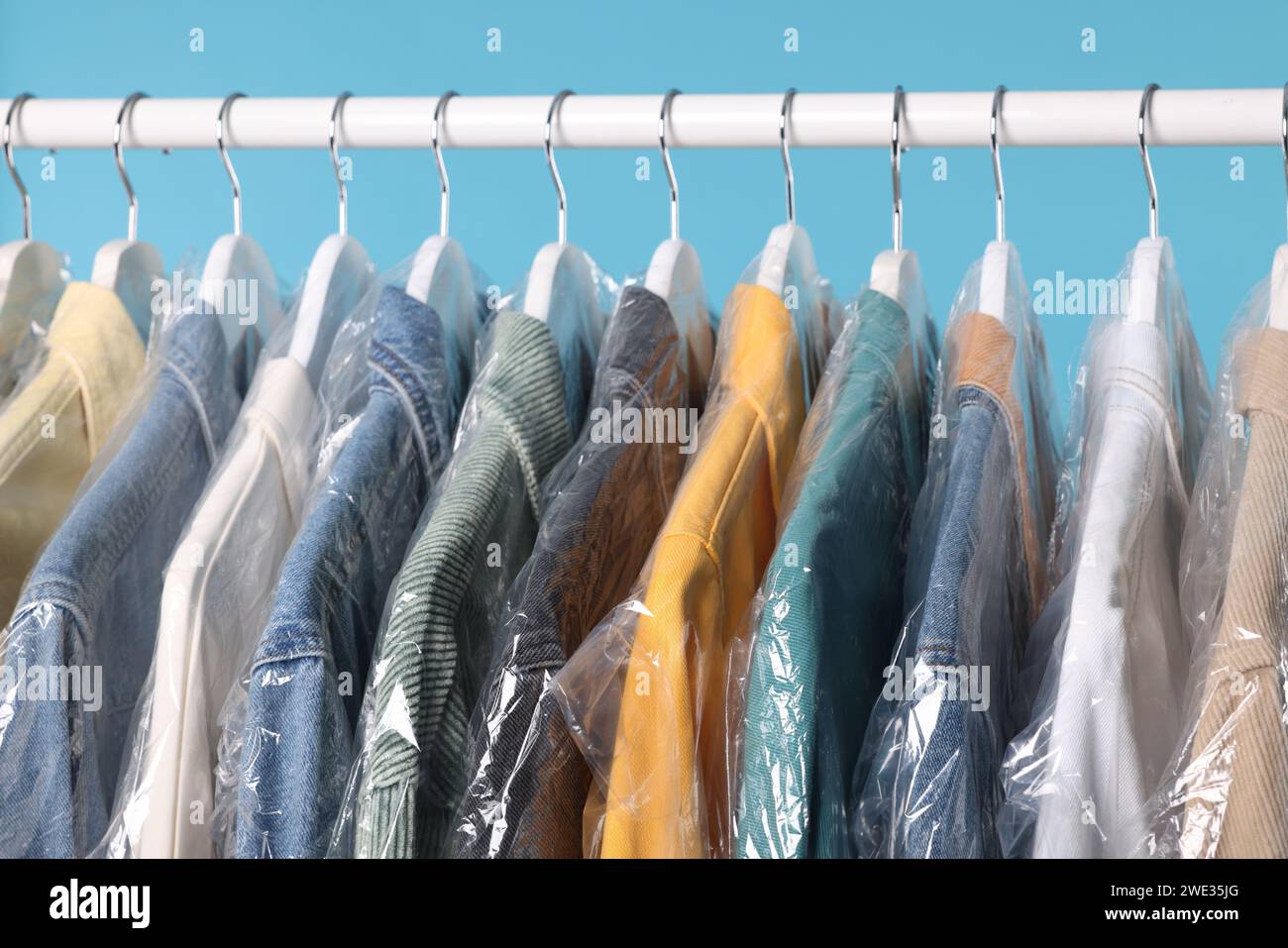 Dry-cleaning service. Many different clothes in plastic bags hanging on ...