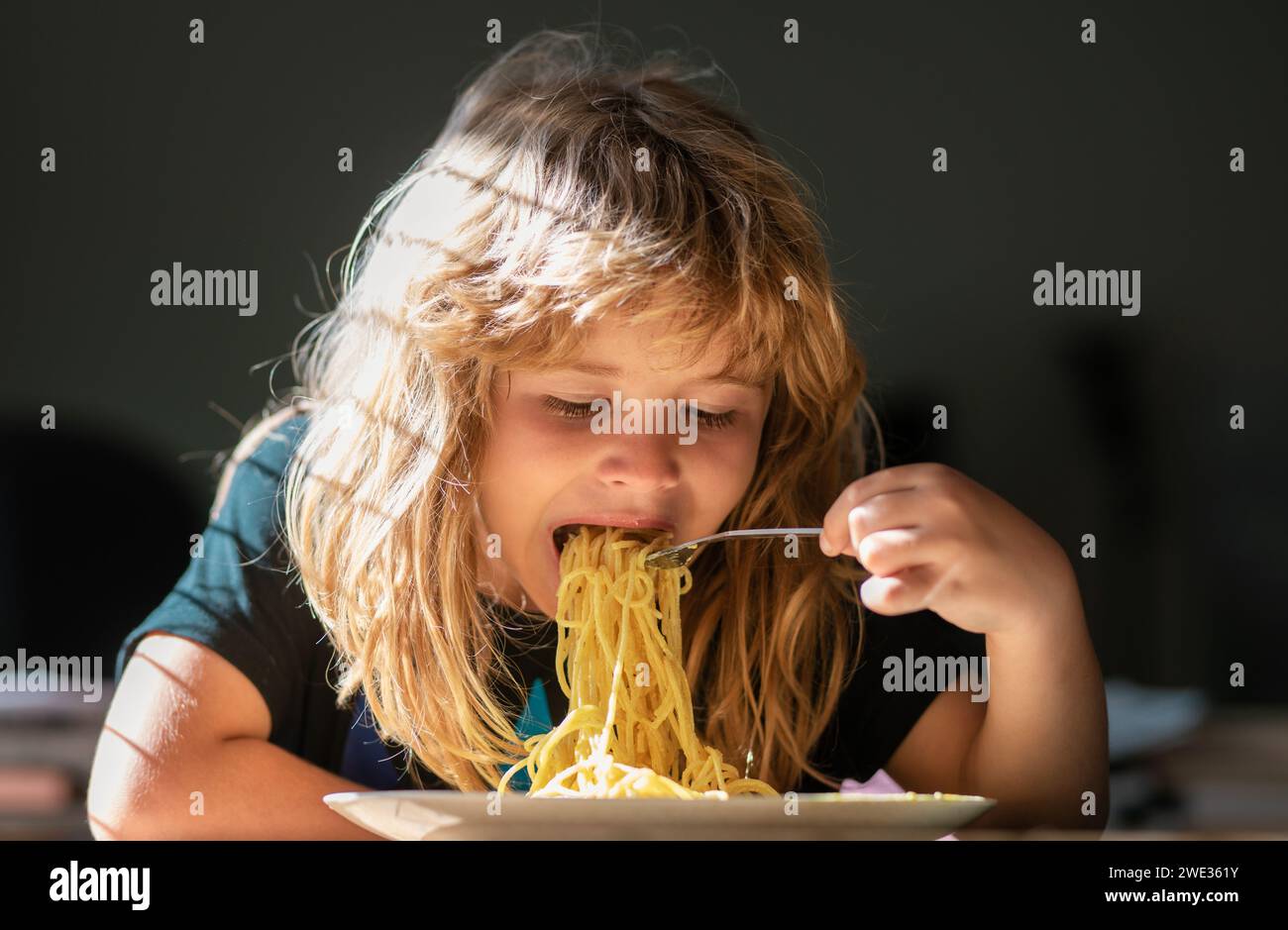 Little kid eating spaghetti in kitchen. Child eating on blurred ...