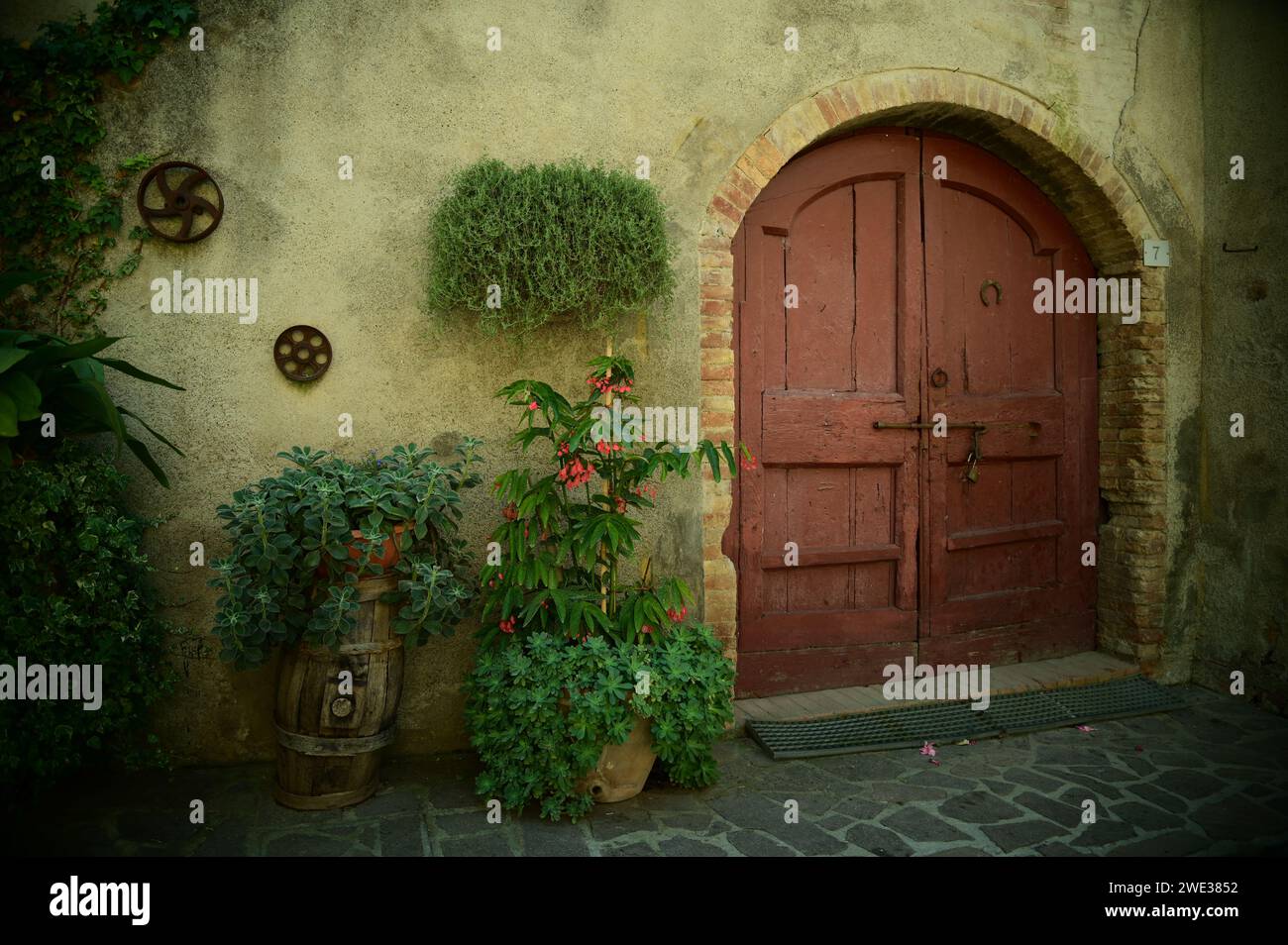 Cozy, rural Italian street scene with a flesh-colored wooden gate ...