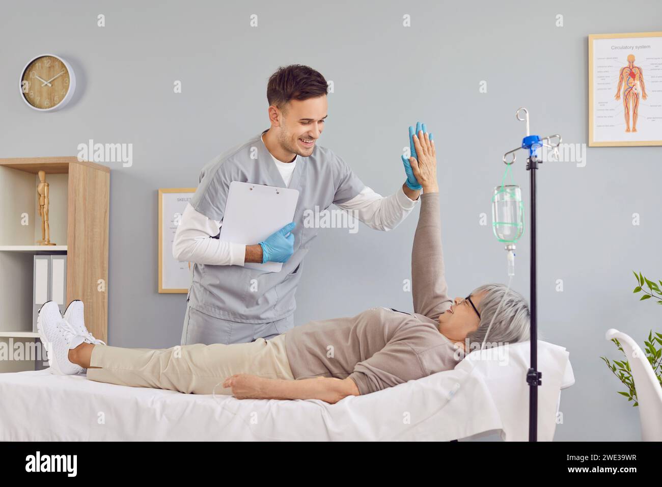 Friendly nurse supporting senior patient who is receiving intravenous ...