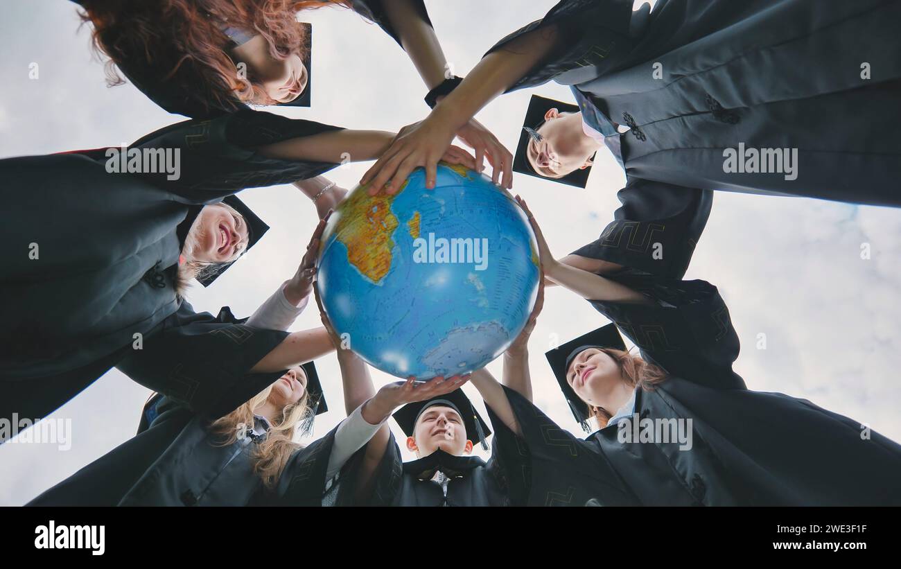 Graduating students twirl a geographic globe of the world in their ...