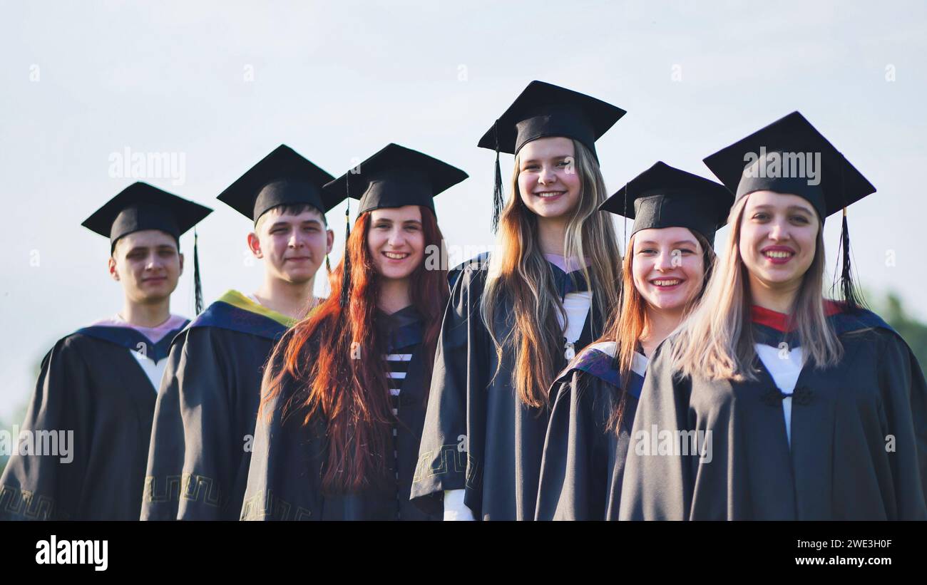 Cheerful graduates pose with raised diplomas on a sunny day Stock Photo ...