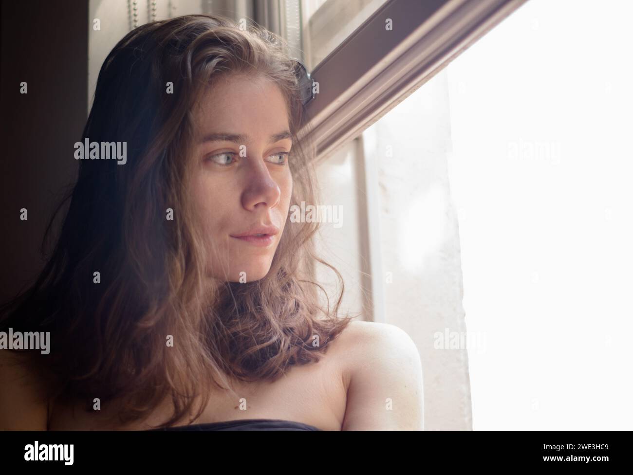Pretty young White woman looking out of a window Stock Photo - Alamy