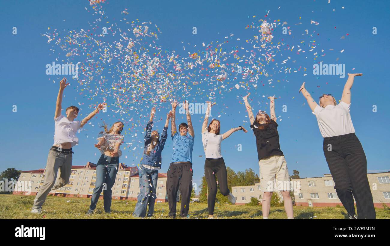 Friends toss colorful paper confetti from their hands Stock Photo - Alamy