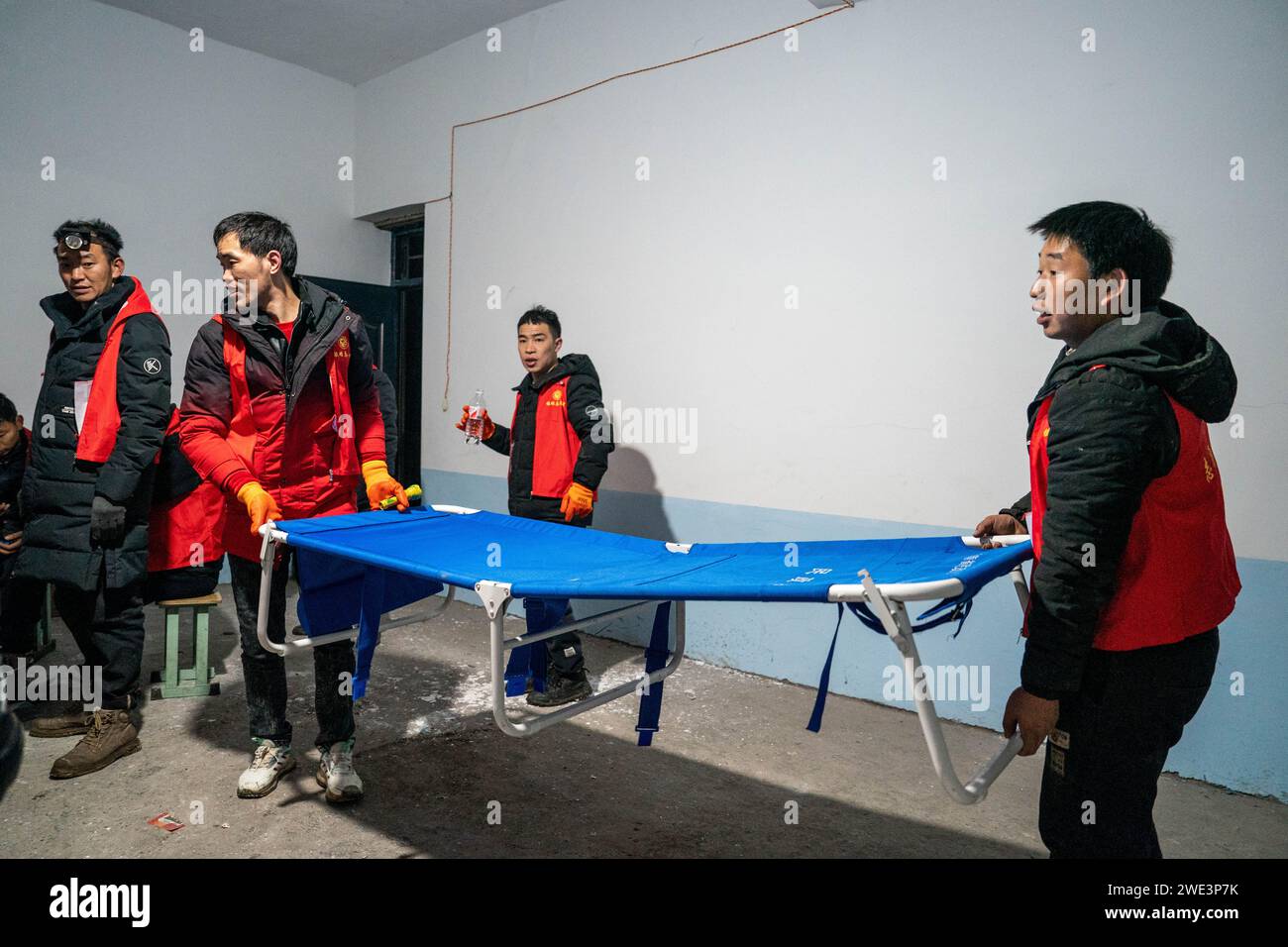 Tangfang Town, China. 23rd Jan, 2024. Villagers transfer a folding bed at a temporary shelter in ...