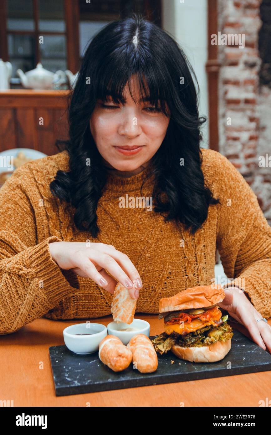 vertical image of young Latina with black hair and brown clothes, happy ...