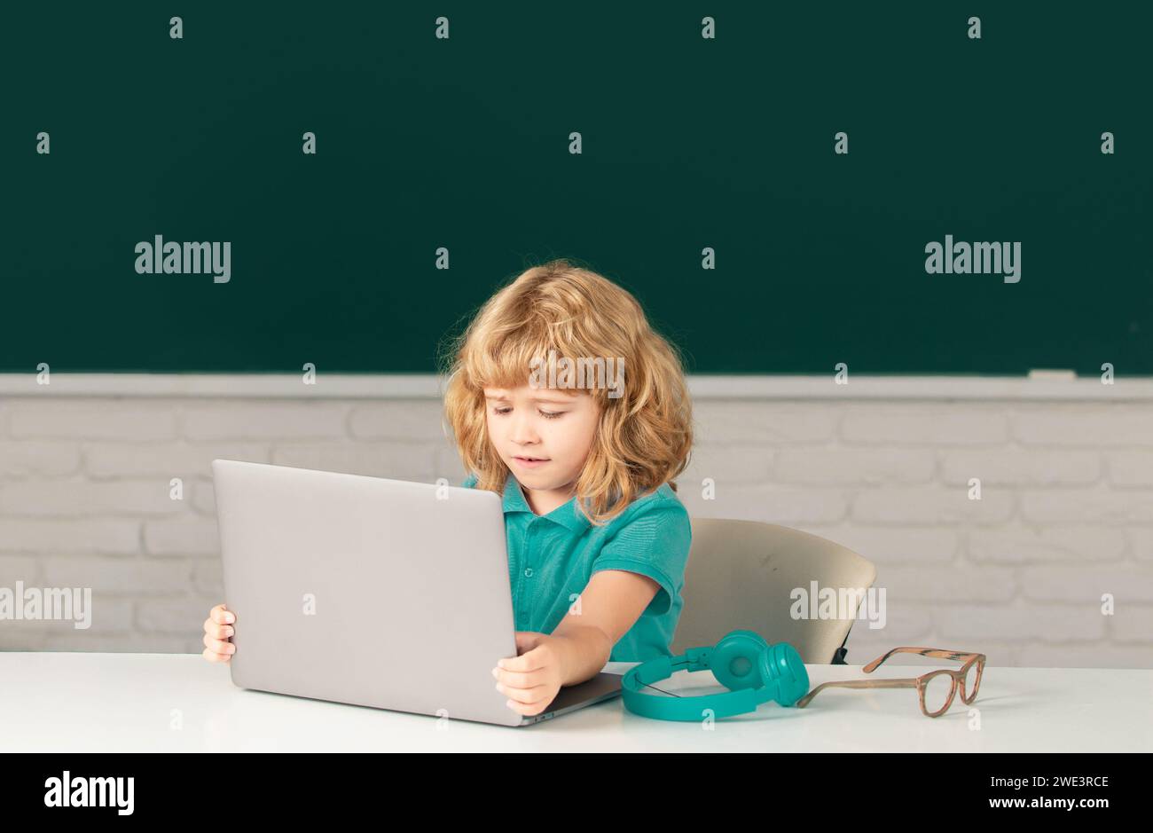 Kid boy learning lesson at school, making homework and using notebook ...