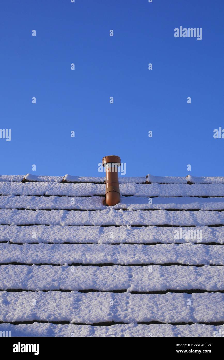 Chimney and snowy roof of a peasant house against a blue sky ...