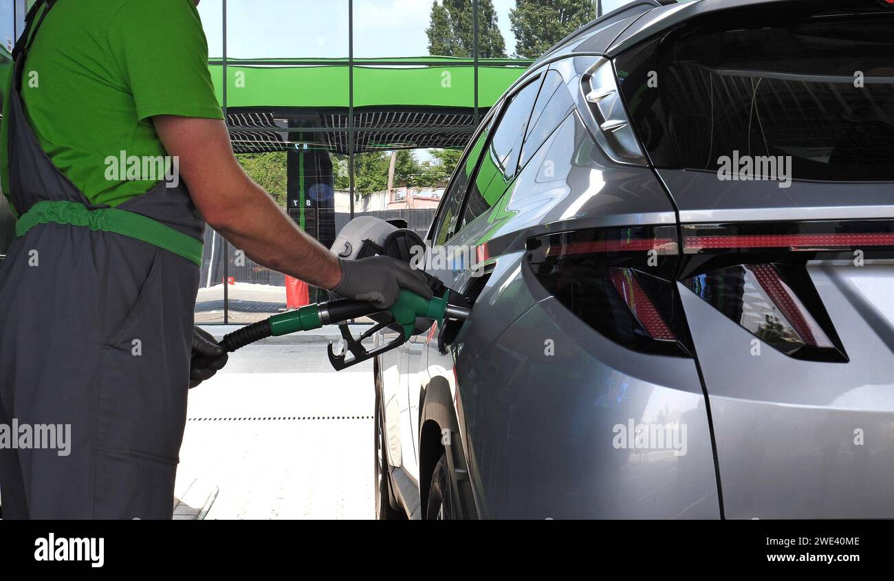 Petrol Station Worker holds a filling nozzle in his hands while ...