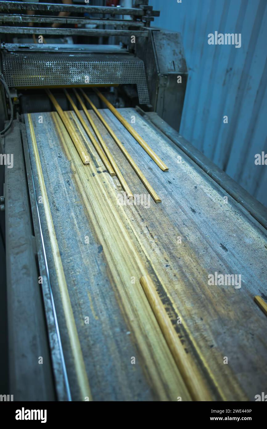 wooden sticks entering lacquering machine Stock Photo - Alamy