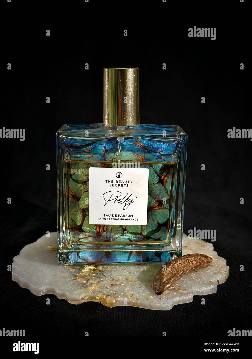 A glowing amber-colored perfume bottle set atop a rock against a ...