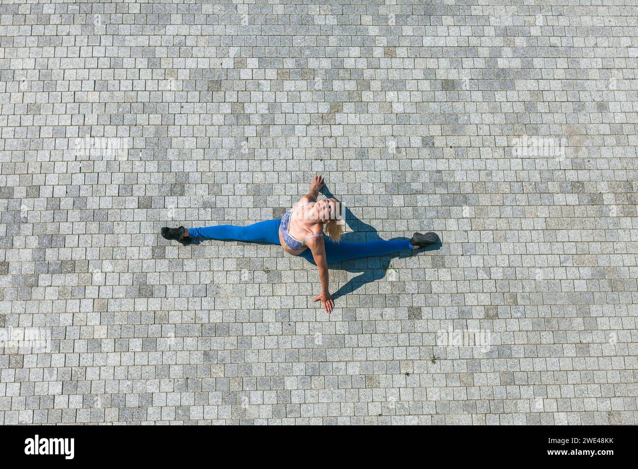 very flexible young woman stretching legs in split position and looking ...