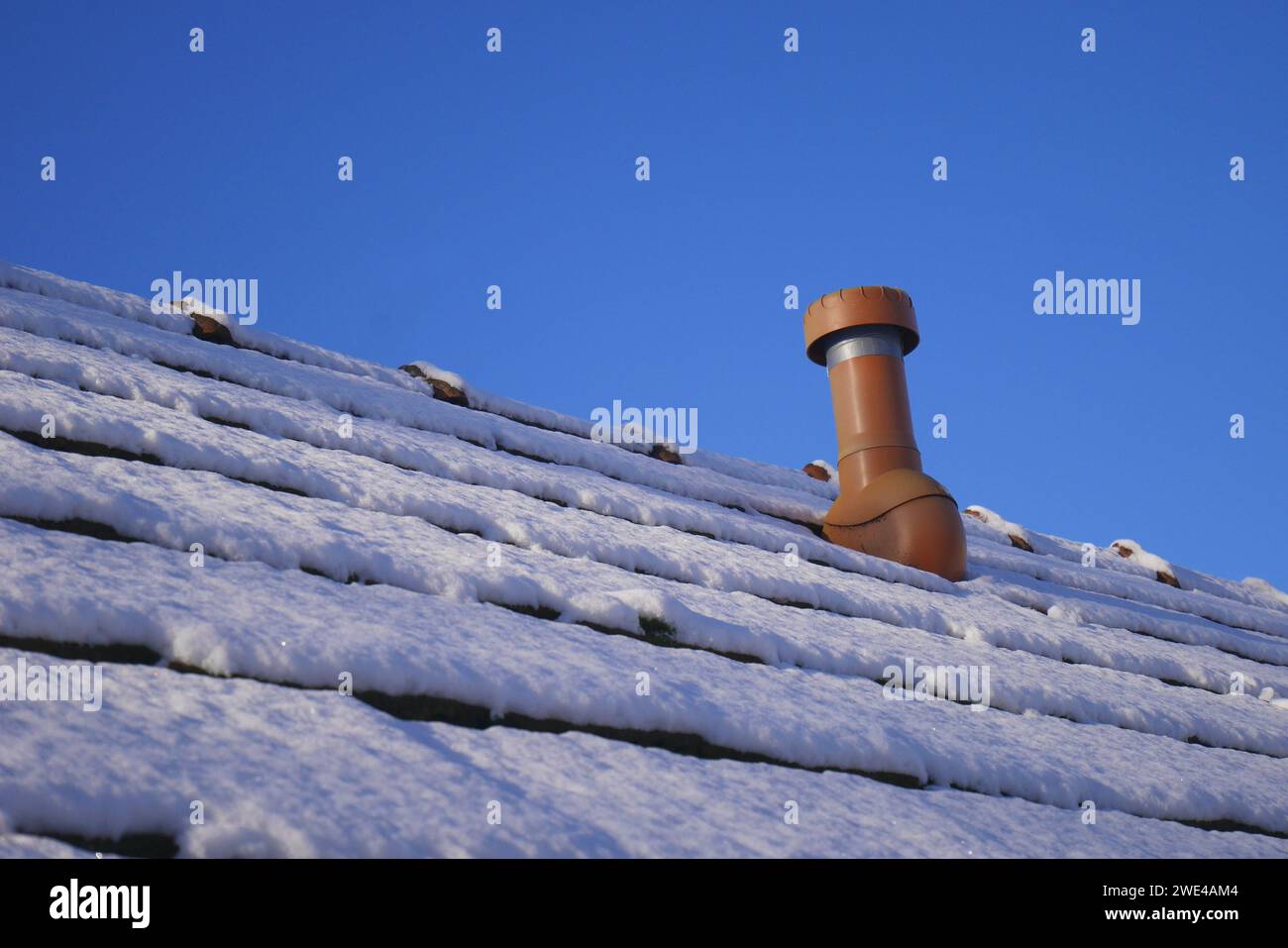 Chimney and snowy roof of a peasant house against a blue sky ...