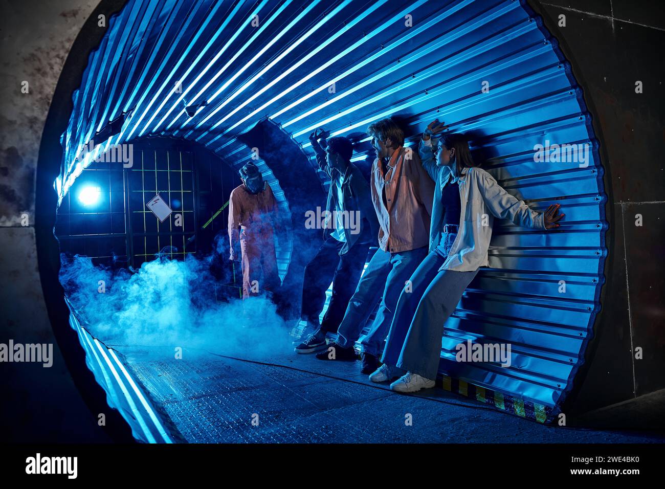 multiethnic friends standing in tunnel near freaky people in gas masks ...