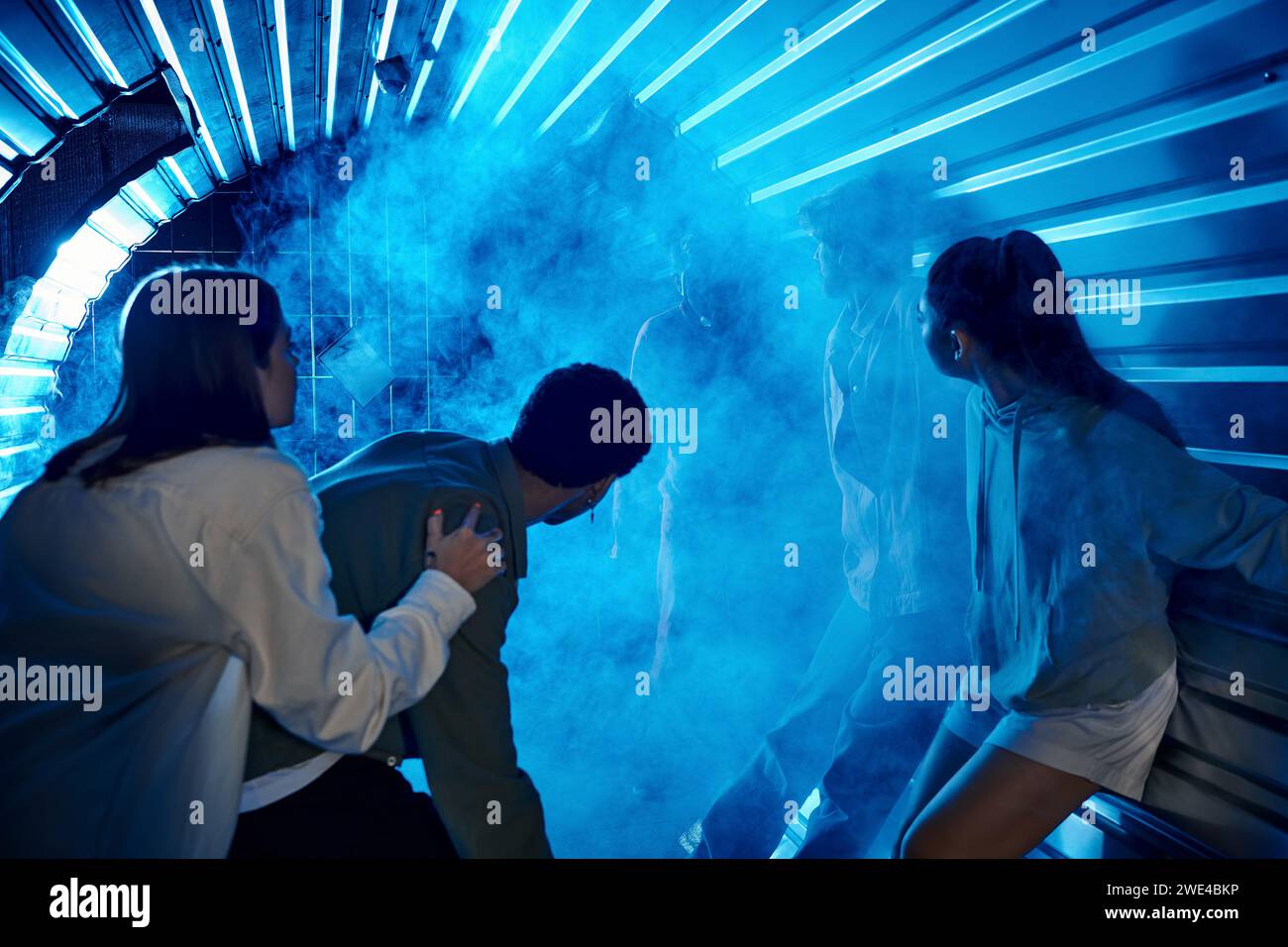 scared diverse friends standing in tunnel near freaky people in gas ...