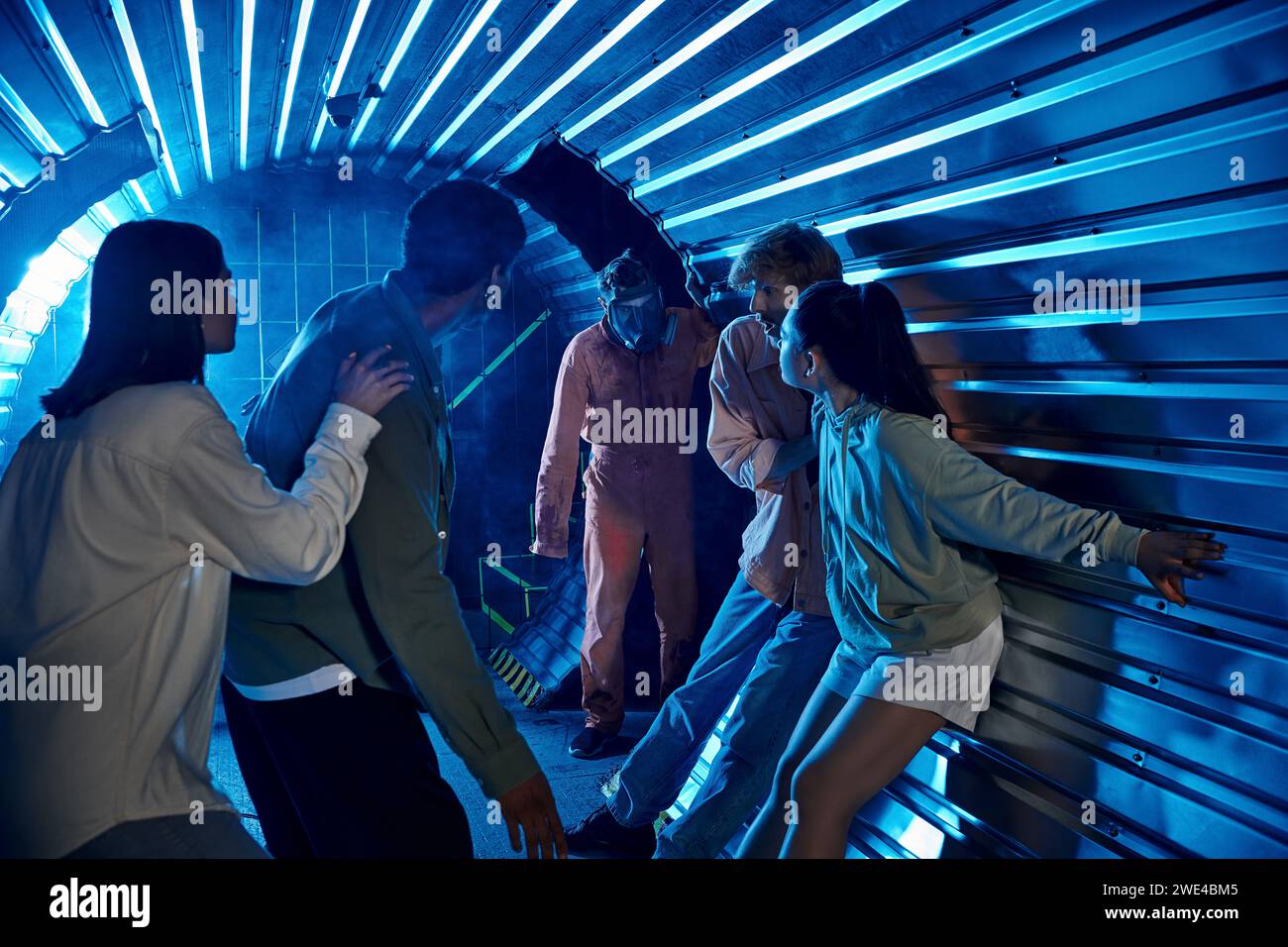 scared diverse friends standing in tunnel near freaky person in gas ...