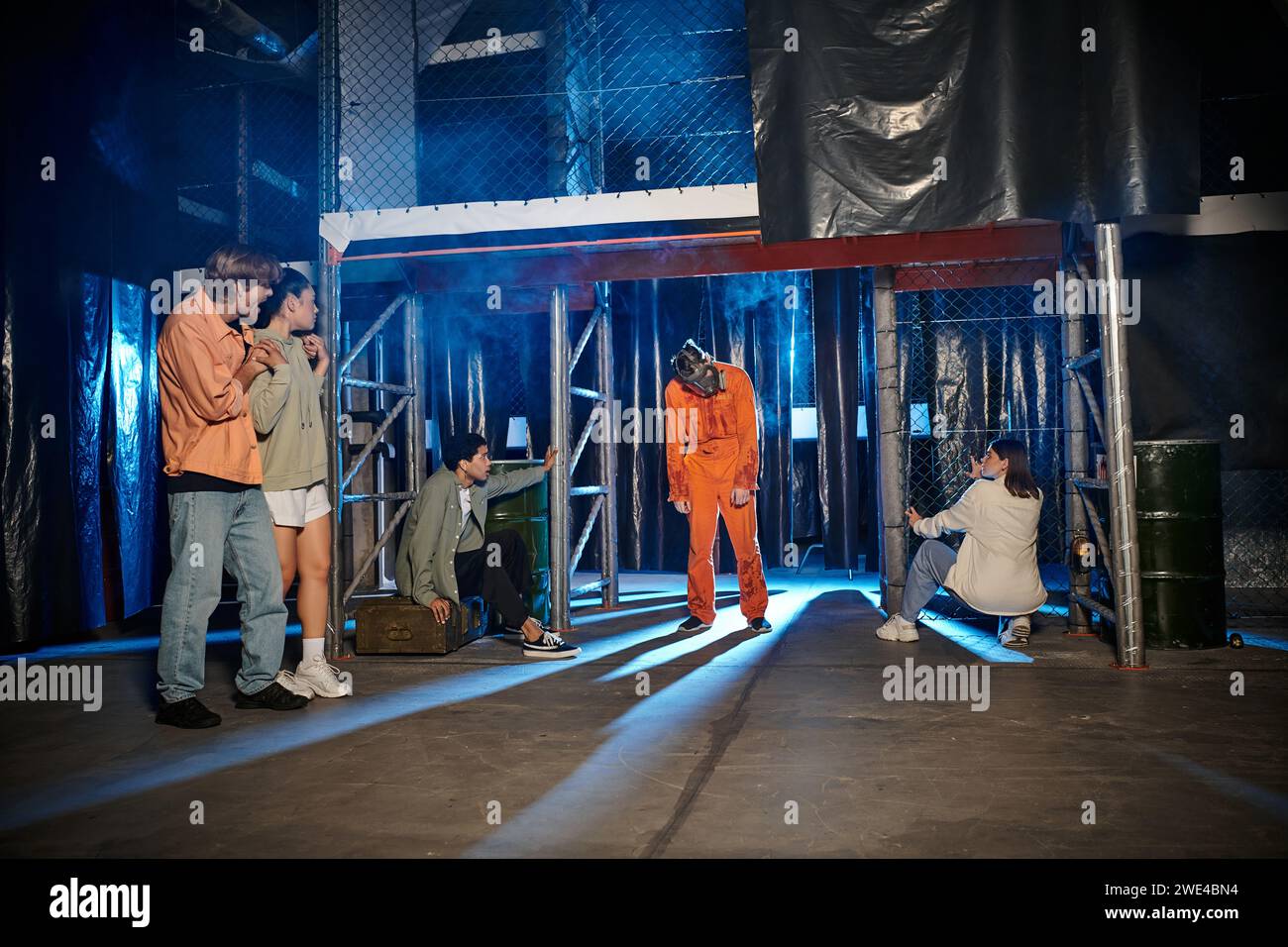 scary person in orange ppe suit and gas mask near group of interracial ...