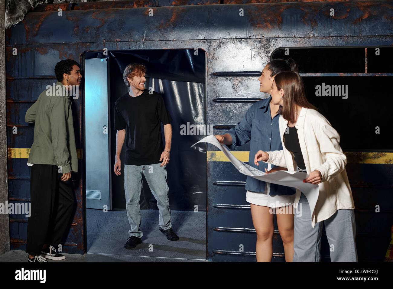 happy interracial girls with map standing near subway wagon and friends ...