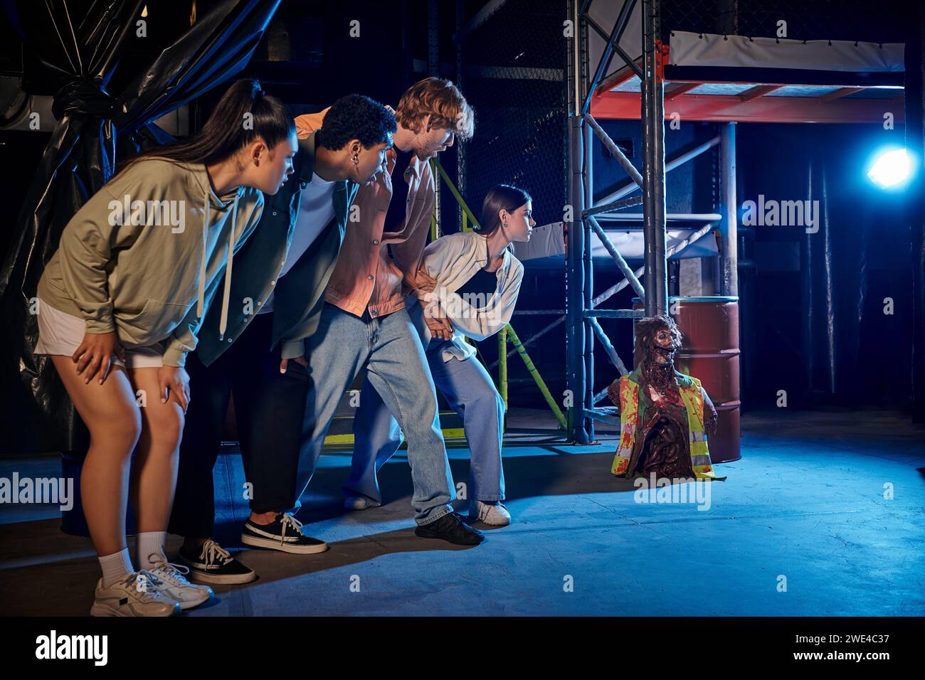 group of diverse and curious young people looking at scary mannequin ...