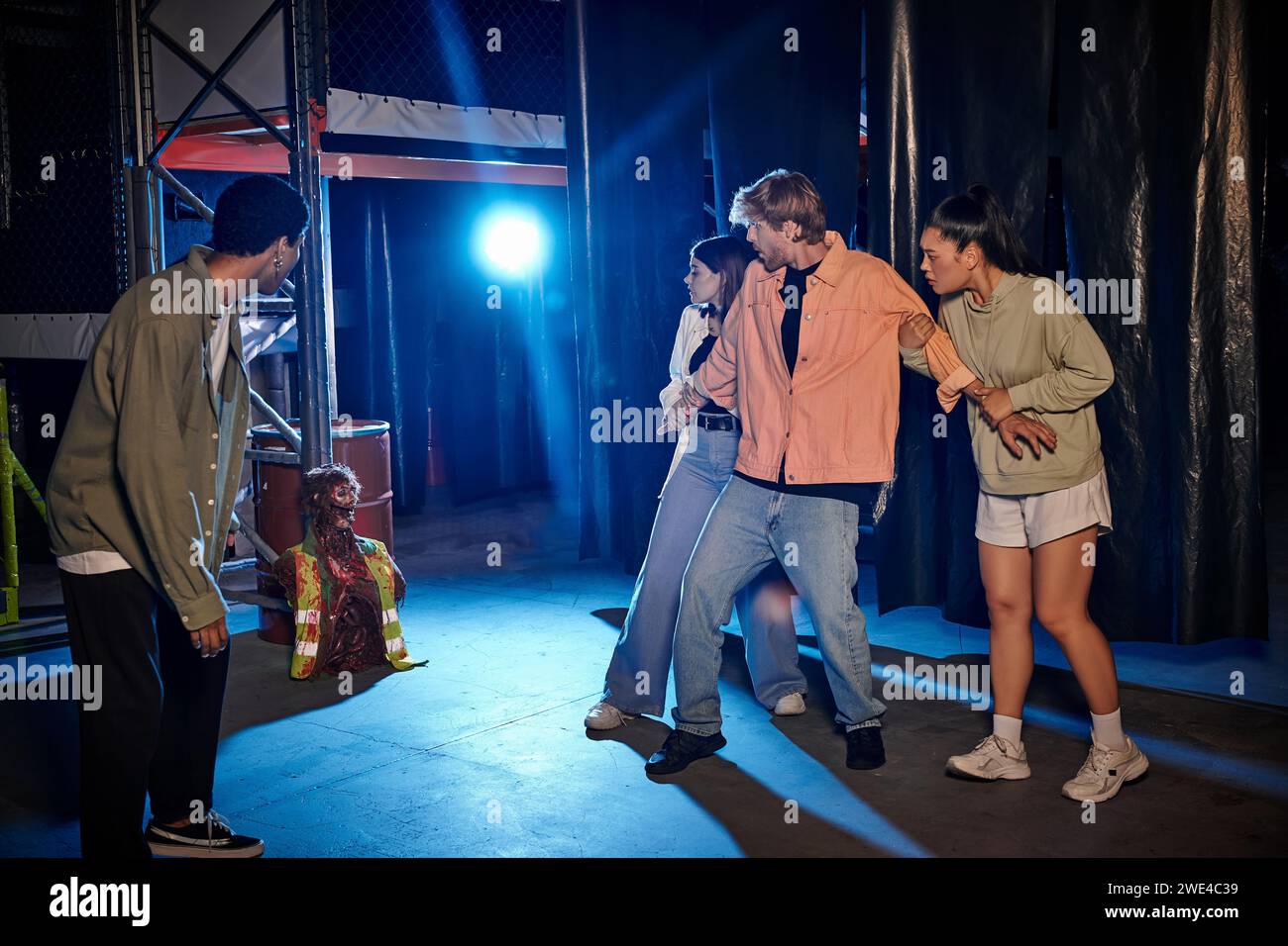 four diverse and curious young people looking at scary mannequin during ...