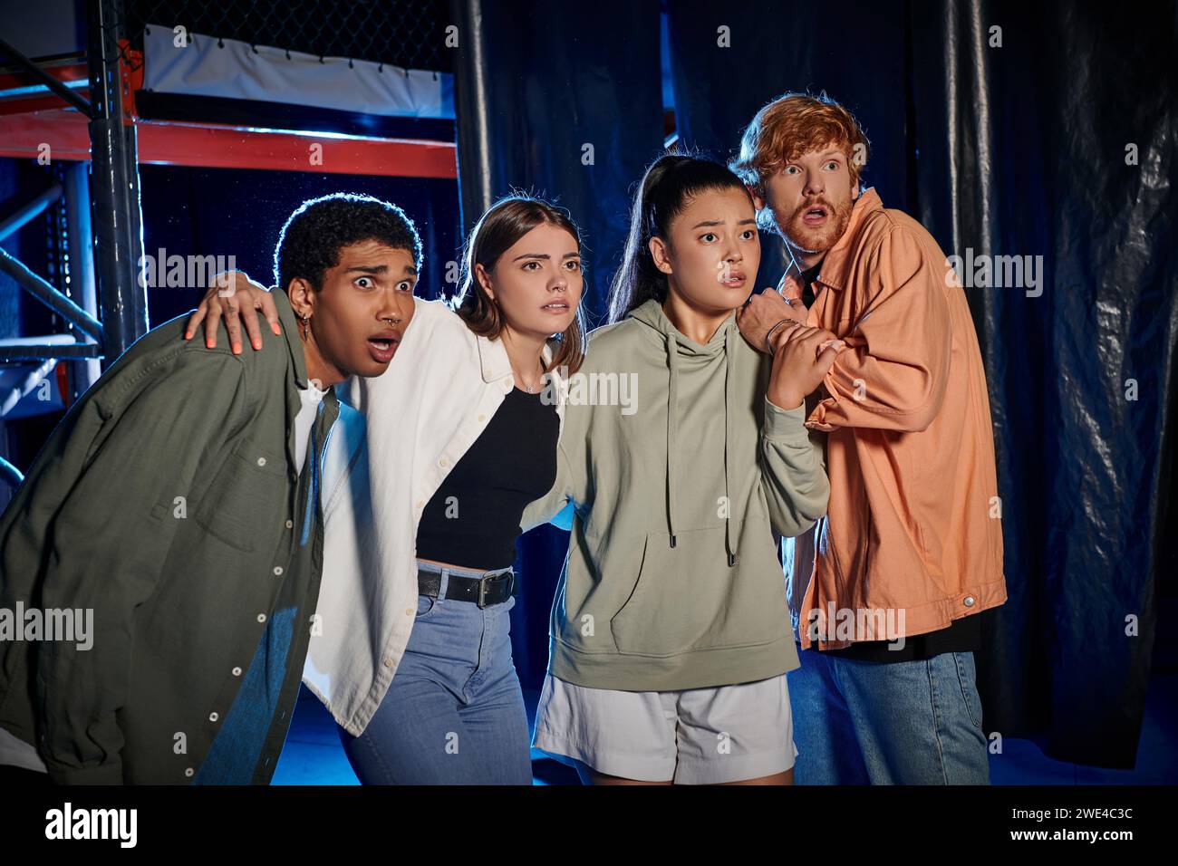 four diverse and scared young people looking at something while ...