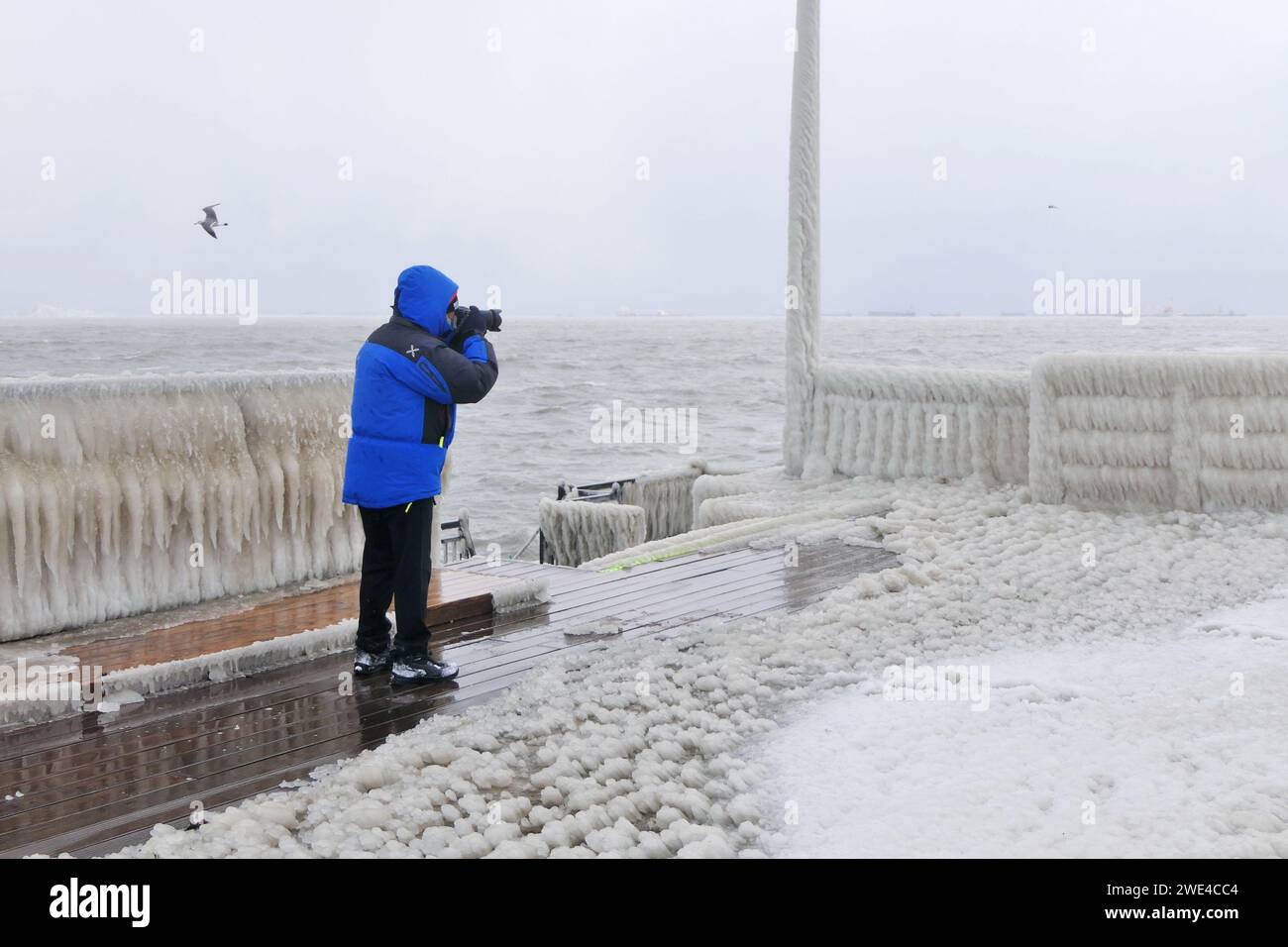 YANTAI, CHINA - JANUARY 22, 2024 - A tourist takes photos of the frozen ...