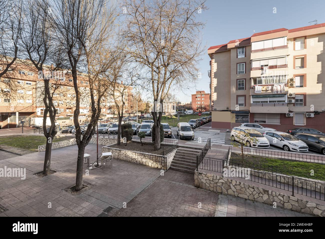 An urban park with clear areas, trees and vehicles parked between the ...